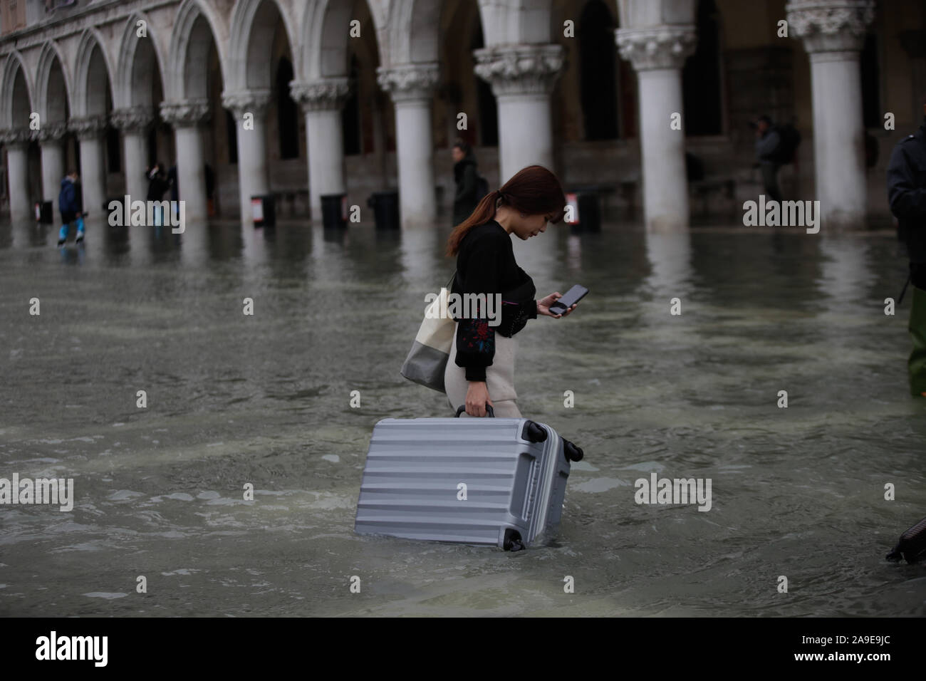 Beijing, Italy. 13th Nov, 2019. A woman walks across the flooded San ...
