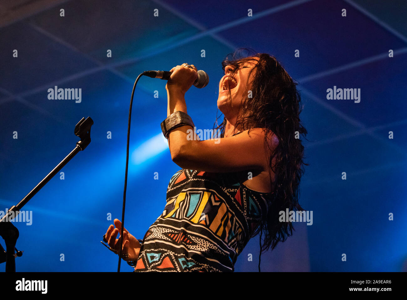 A female musician is viewed from a low angle as she sings, with open ...