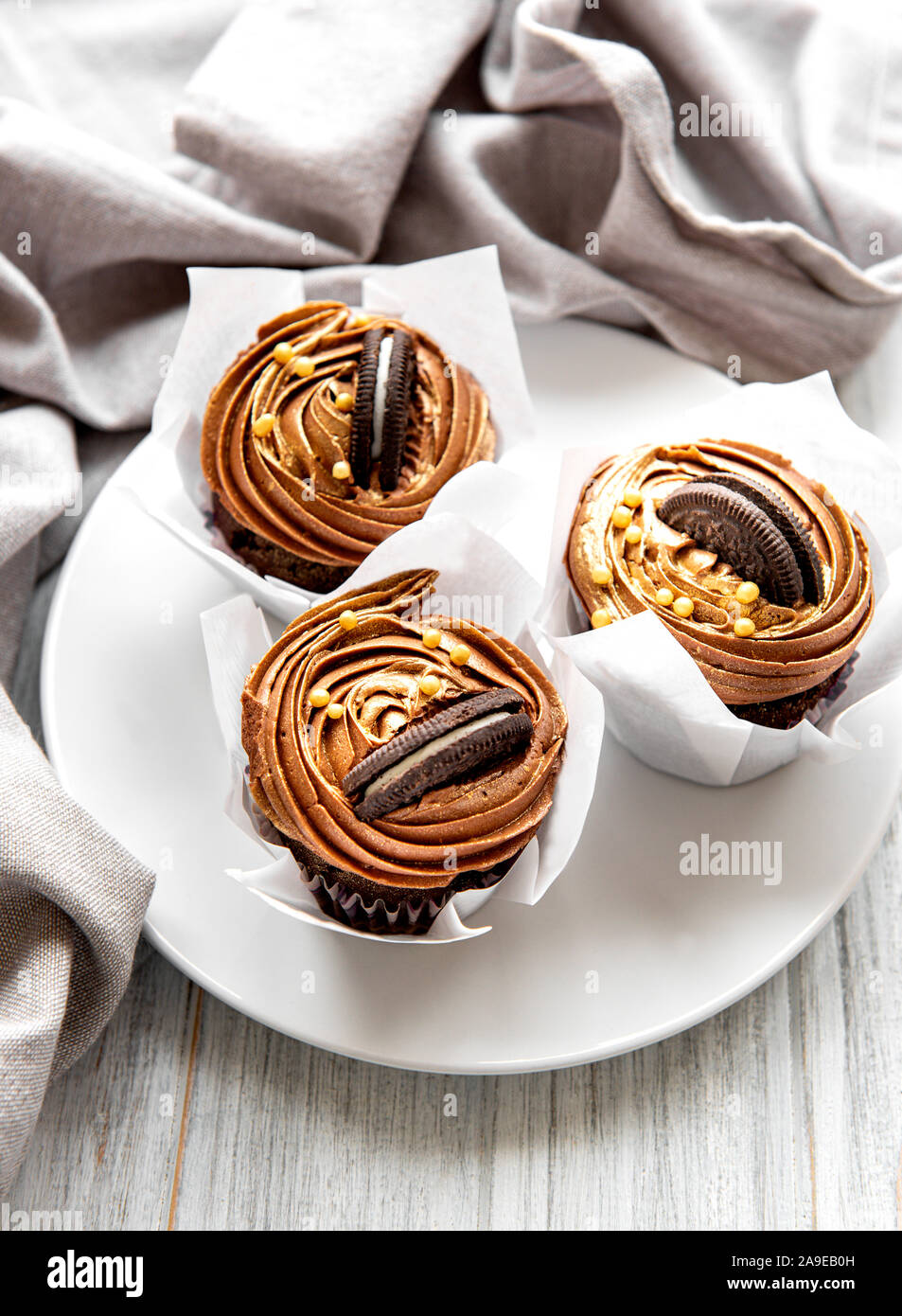 Cupcakes or muffins with chocolate cream on white wooden background ...