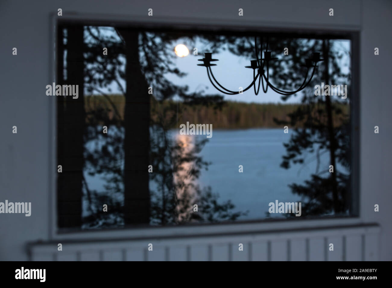 Finland, Lapland, Kuusamo, mirroring of scenery with moon in window ...