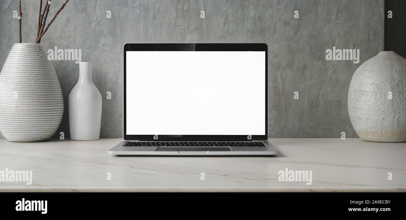 Minimal workspace with blank screen laptop computer and ceramic vase ...