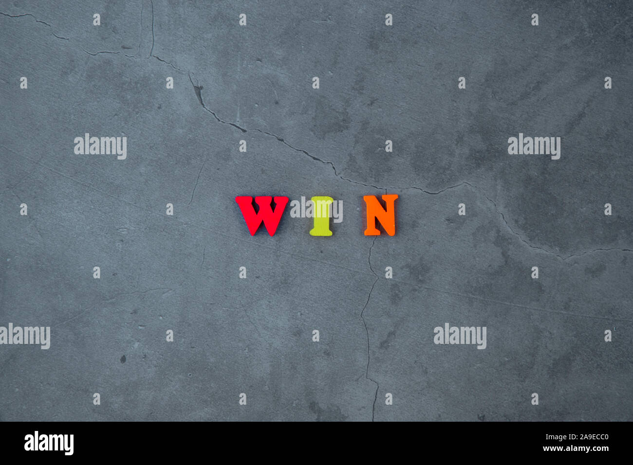 The multicolored win word is made of wooden letters on a grey plastered ...