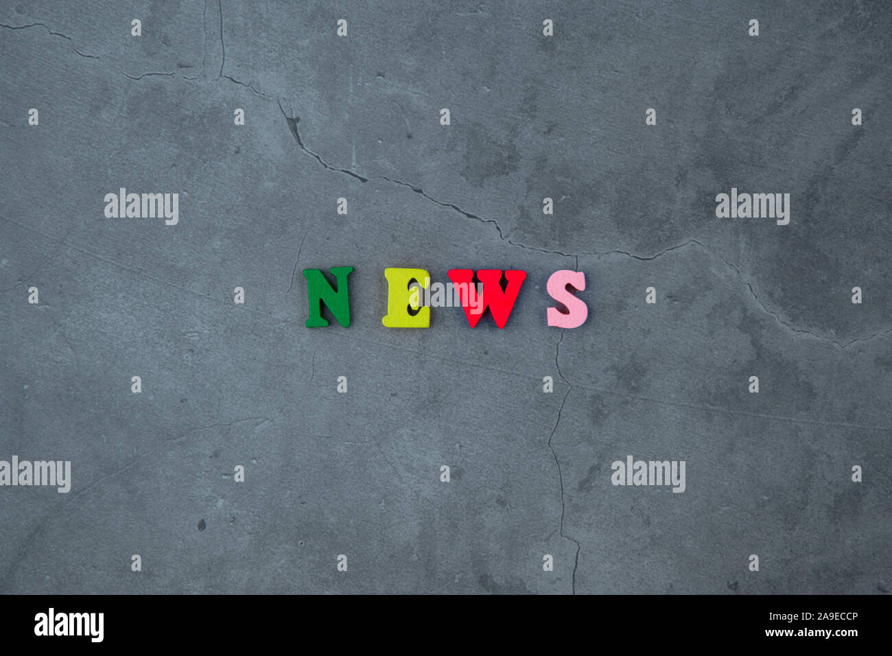 The multicolored news word is made of wooden letters on a grey ...