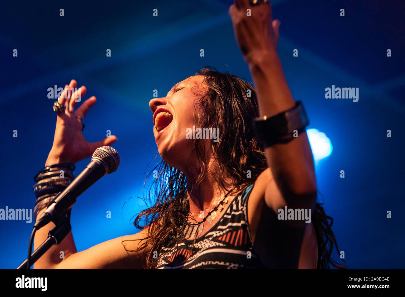 A female musician is viewed from a low angle as she sings, with open ...