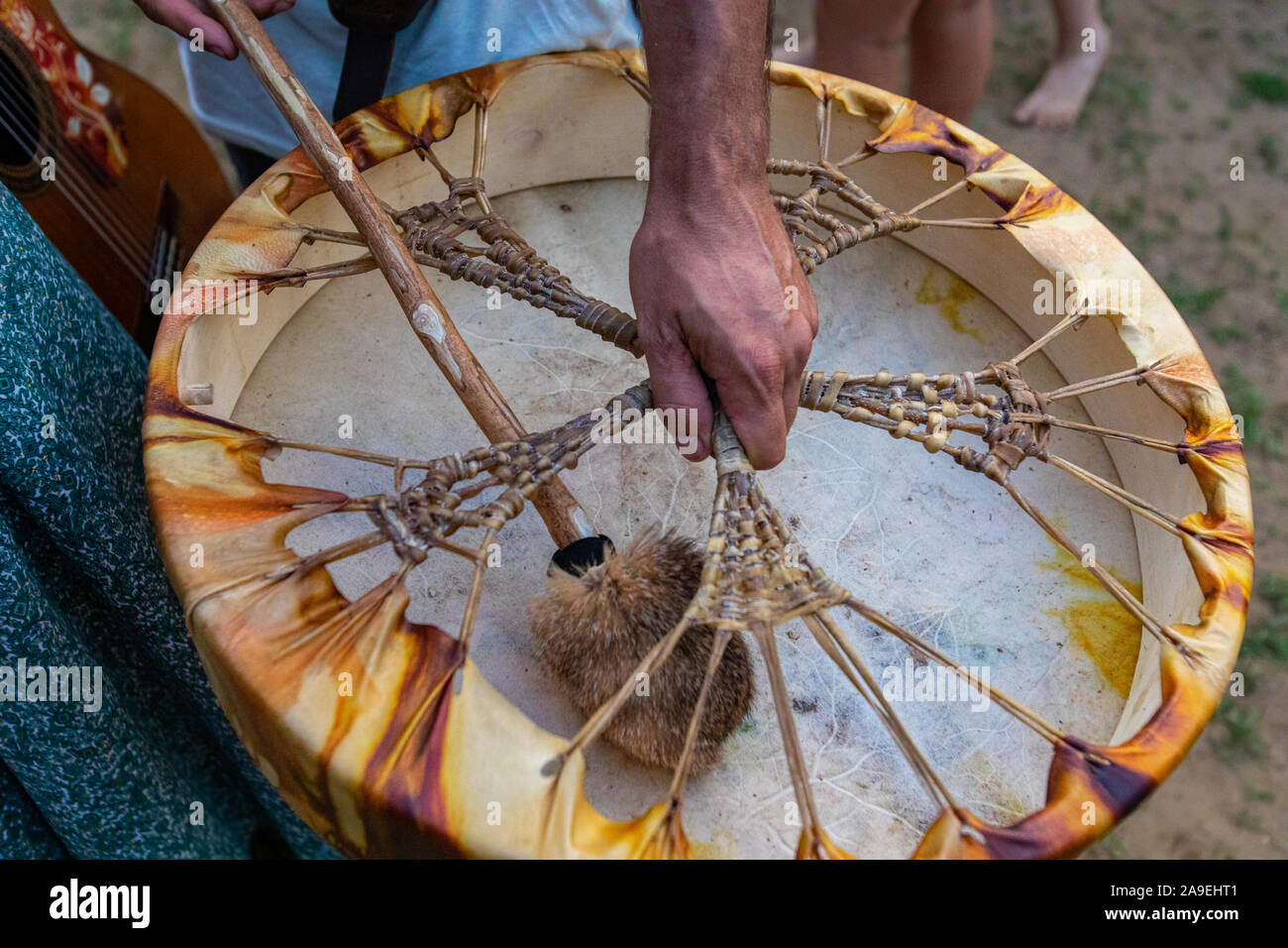 A close-up view of a person's hand holding a traditional native drum ...