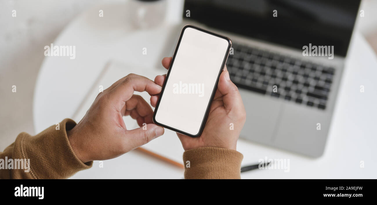 Top view of young man holding blank screen smartphone while working the ...