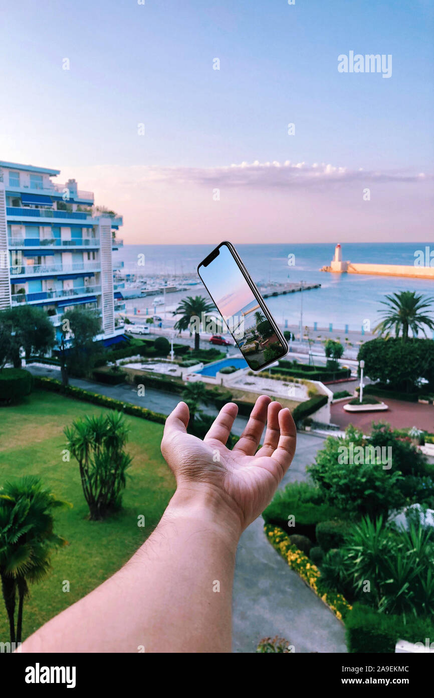 Male hand throw off a mobile phone with background of Nice ...