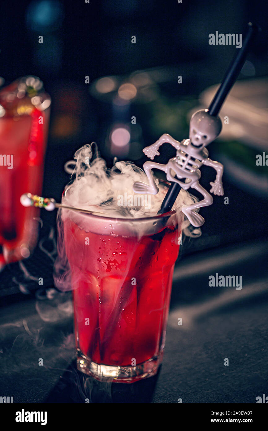 Halloween festive drink, red cocktail with smoke on night dark ...