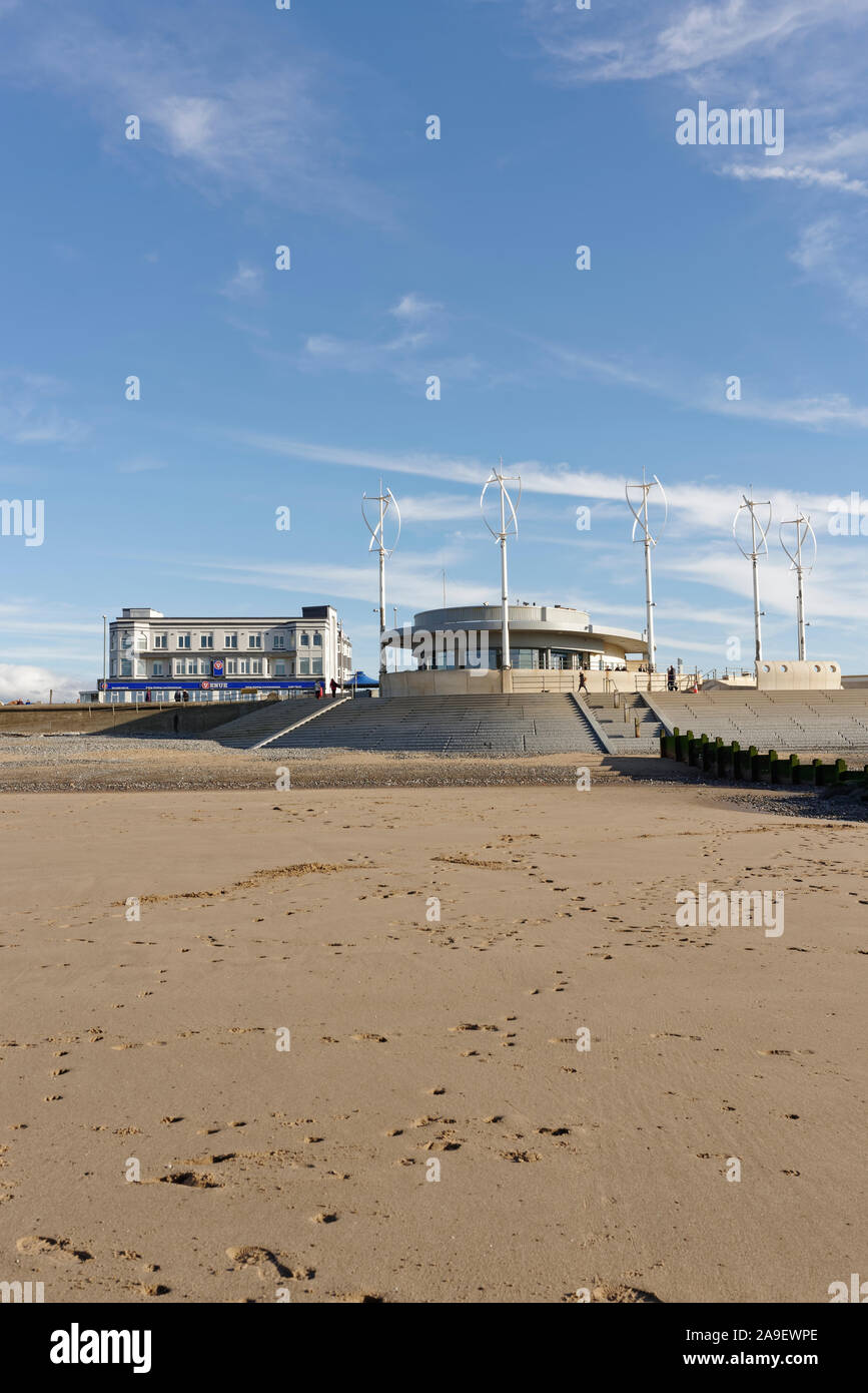 Beach at low tide with seafront cafe and horizontal axis wind turbines ...