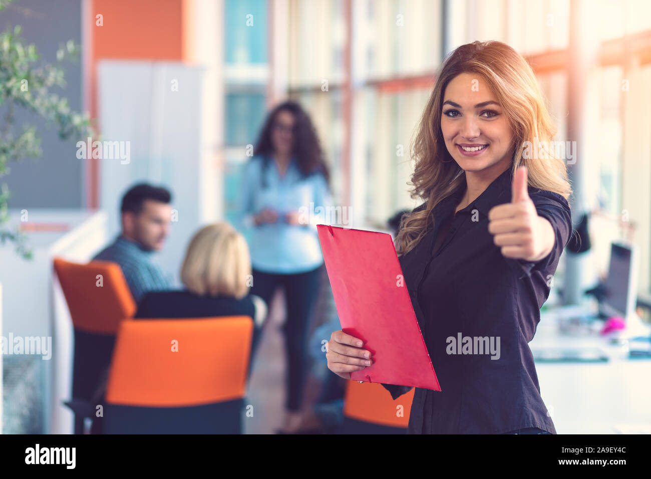 Business woman with folders standing and team mates working in meeting ...