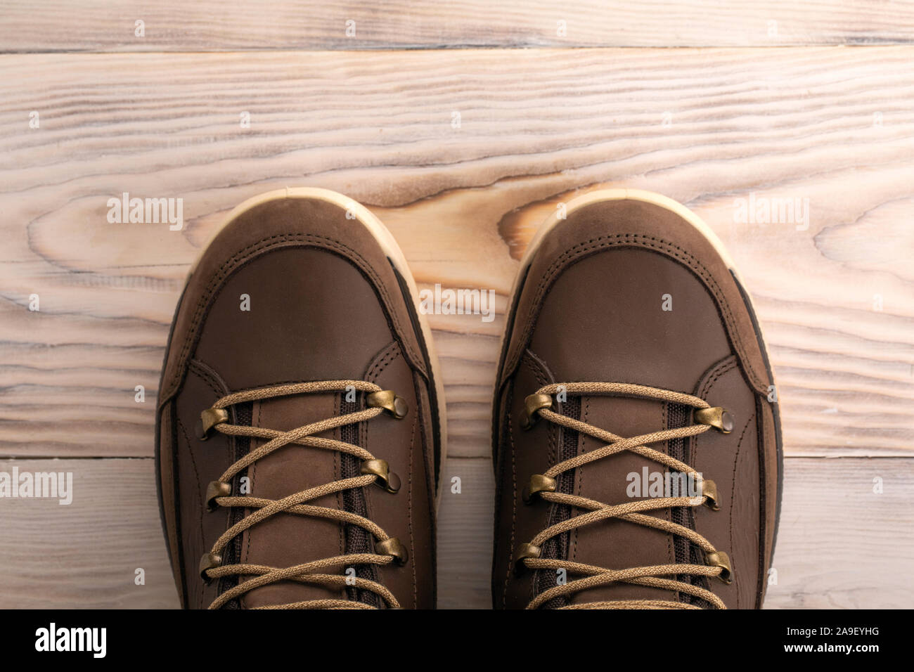 Pair of unisex brown leather boots on a wood board background. Flat lay ...