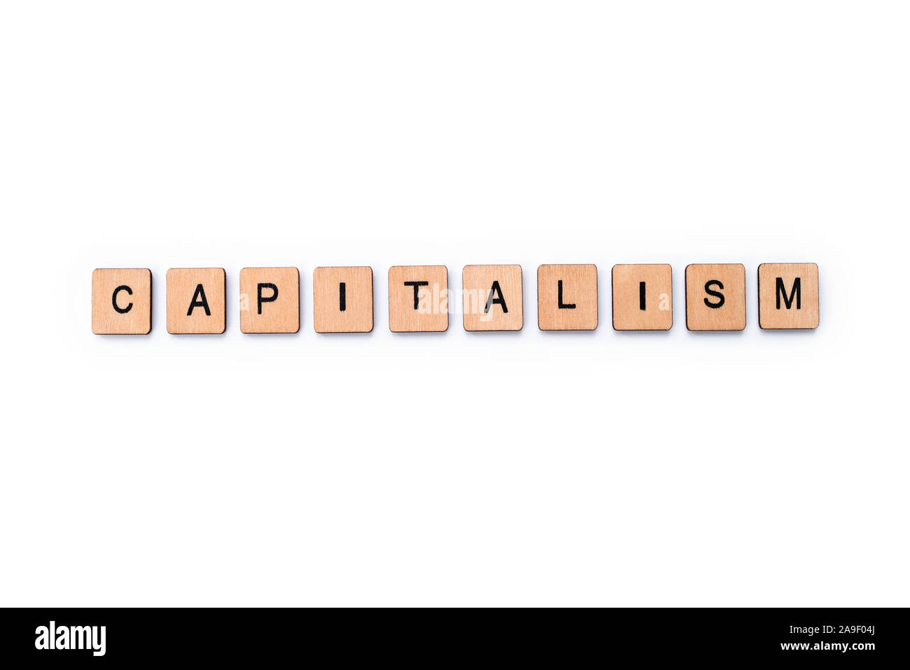 The word CAPITALISM, spelt with wooden letter tiles over a plain white ...