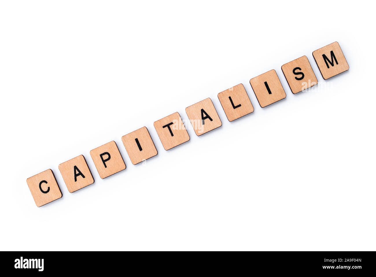 The word CAPITALISM, spelt with wooden letter tiles over a plain white ...