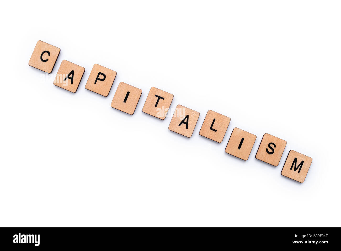 The word CAPITALISM, spelt with wooden letter tiles over a plain white ...