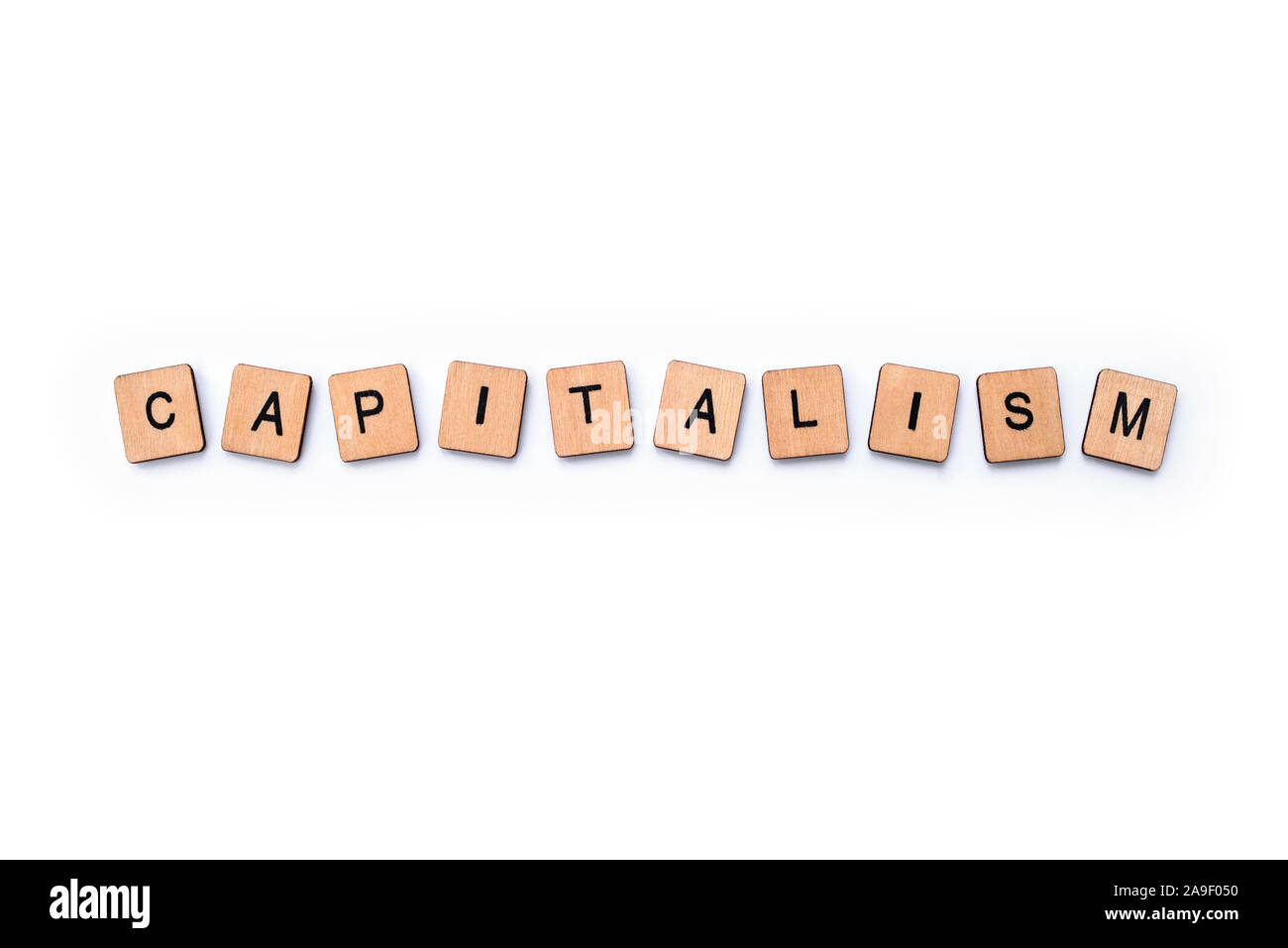 The word CAPITALISM, spelt with wooden letter tiles over a plain white ...