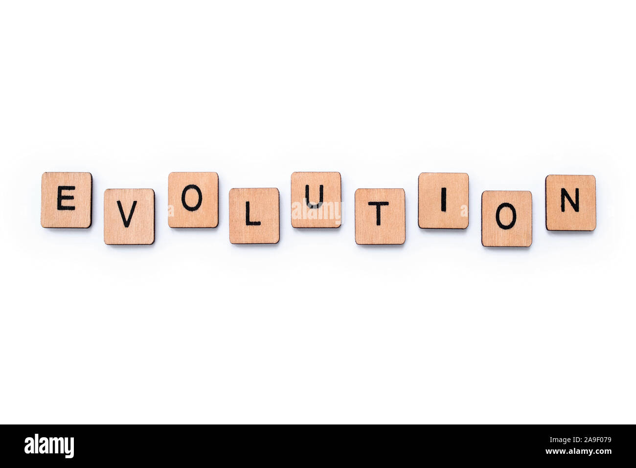 The word EVOLUTION, spelt with wooden letter tiles over a plain white ...