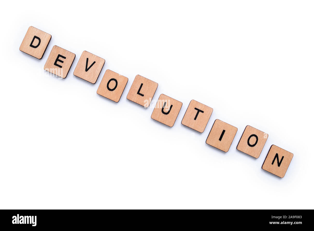 The word DEVOLUTION, spelt with wooden letter tiles over a plain white ...