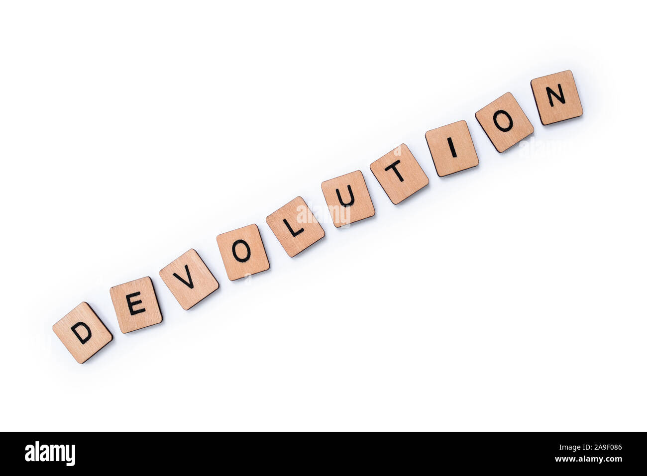 The word DEVOLUTION, spelt with wooden letter tiles over a plain white ...