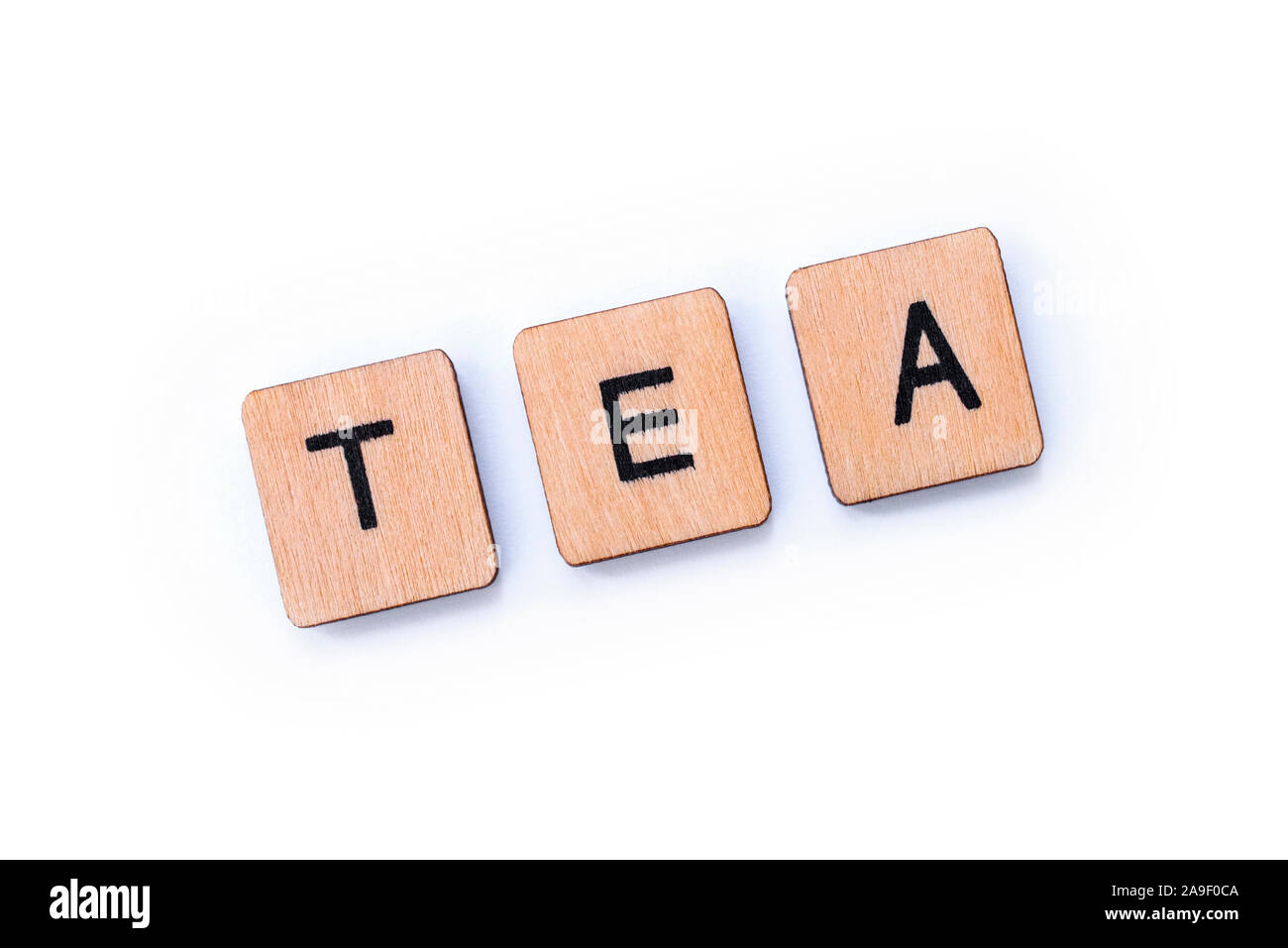 The word TEA, spelt with wooden letter tiles over a white background ...