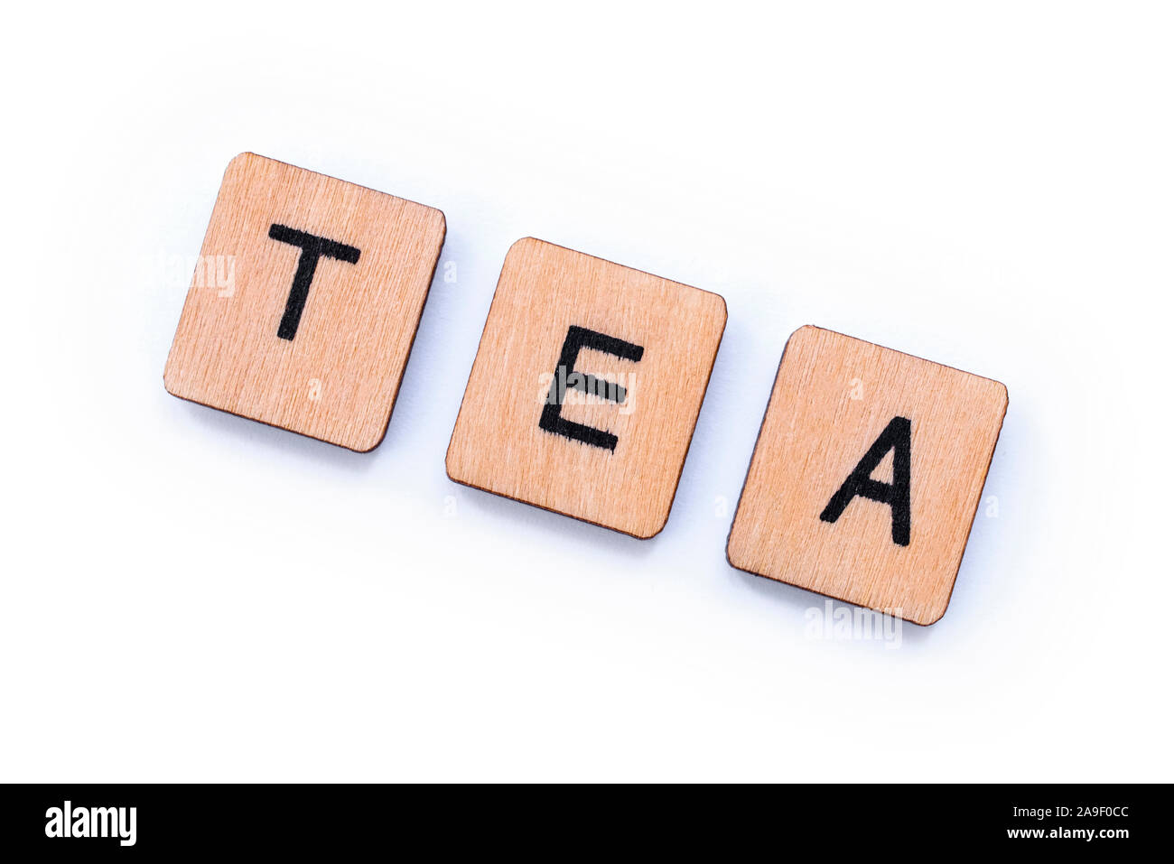 The word TEA, spelt with wooden letter tiles over a white background ...