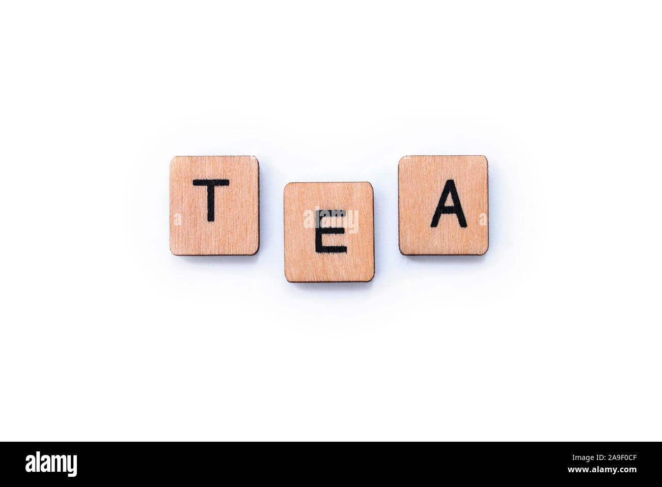The word TEA, spelt with wooden letter tiles over a white background ...