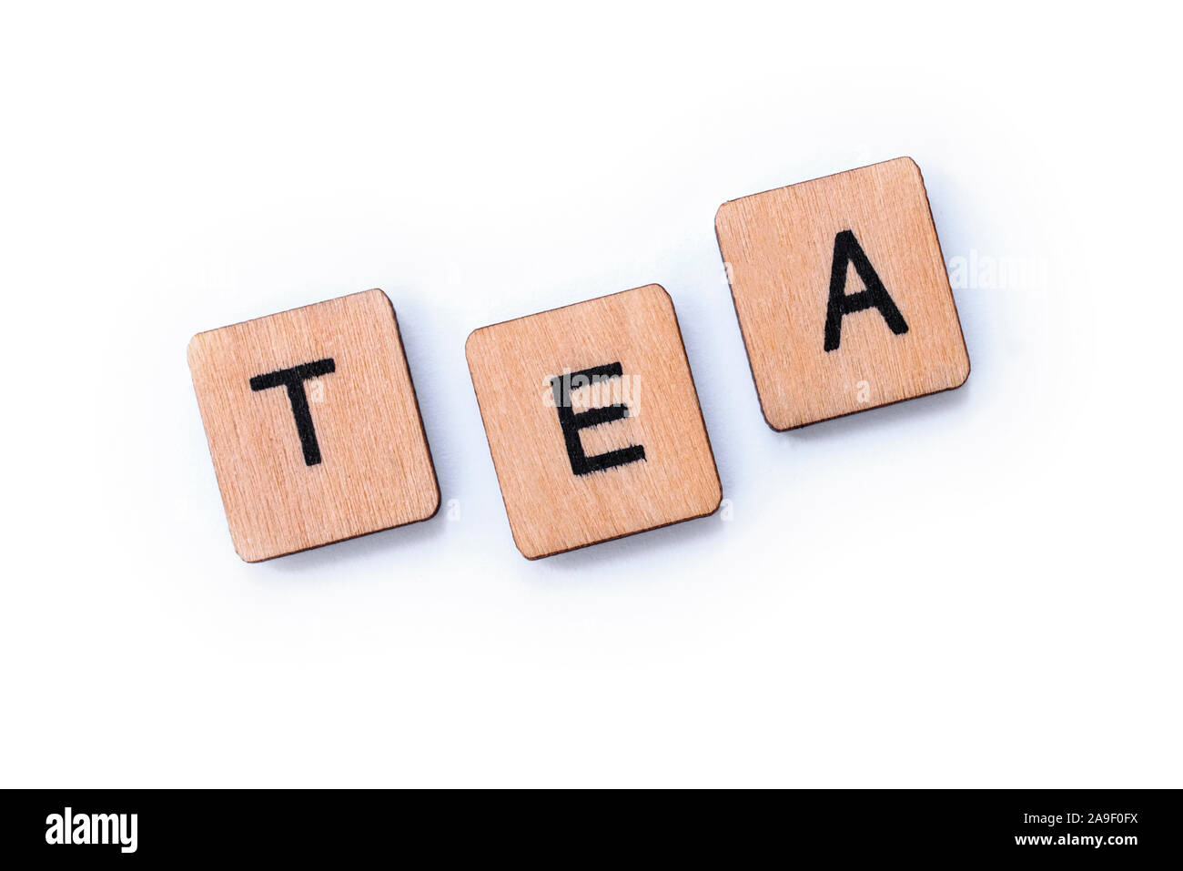 The word TEA, spelt with wooden letter tiles over a white background ...