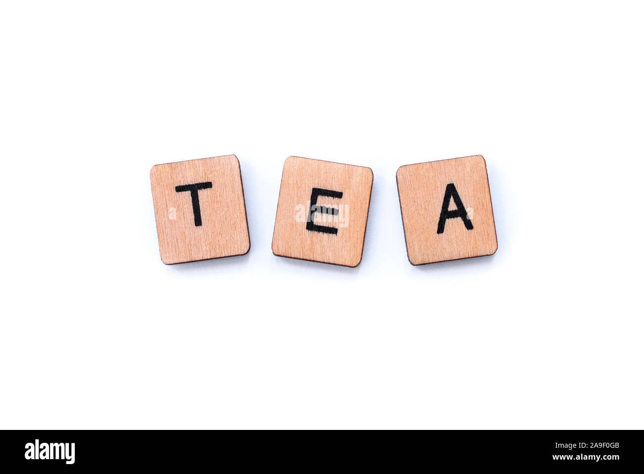The word TEA, spelt with wooden letter tiles over a white background ...