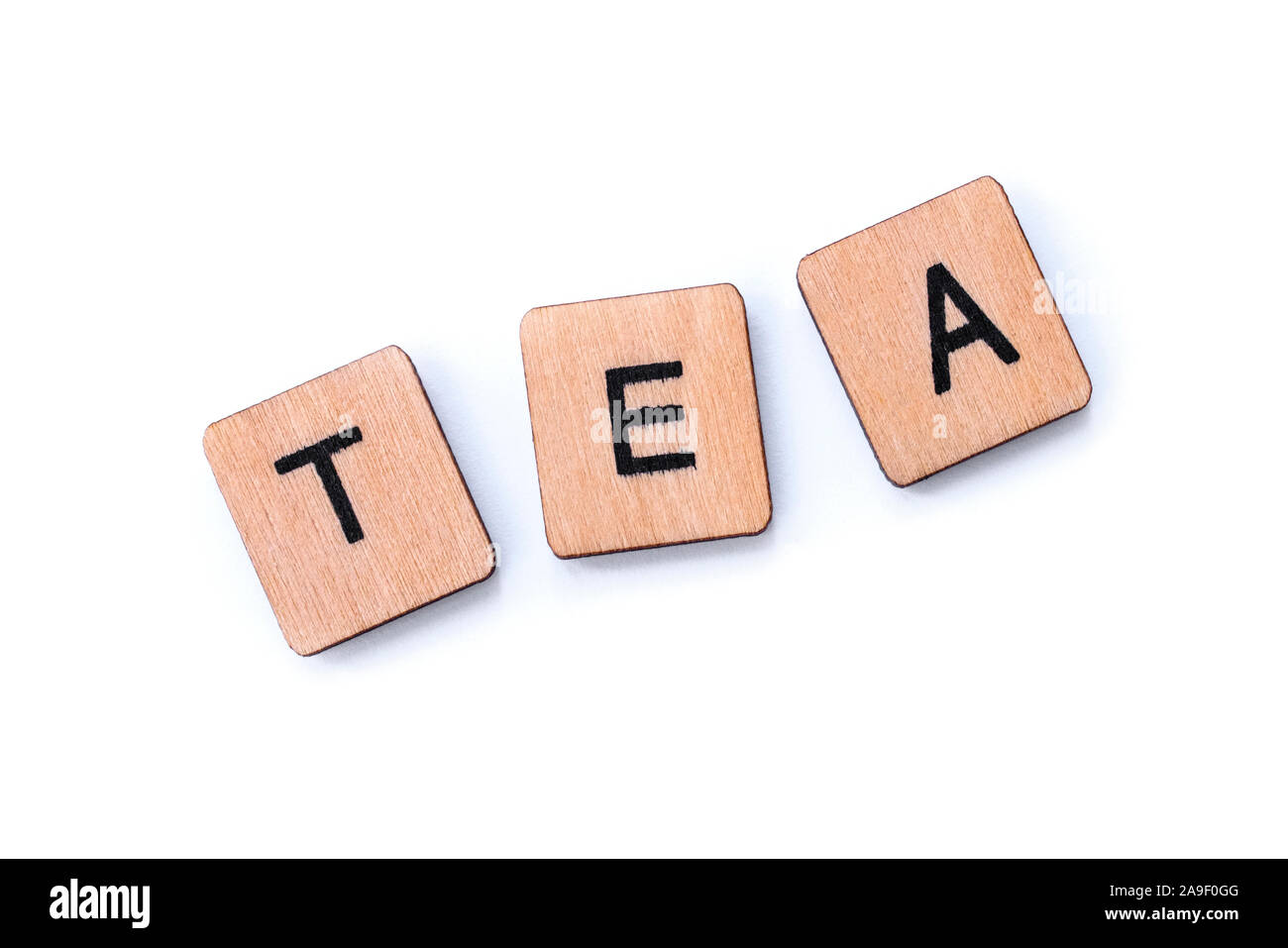 The word TEA, spelt with wooden letter tiles over a white background ...