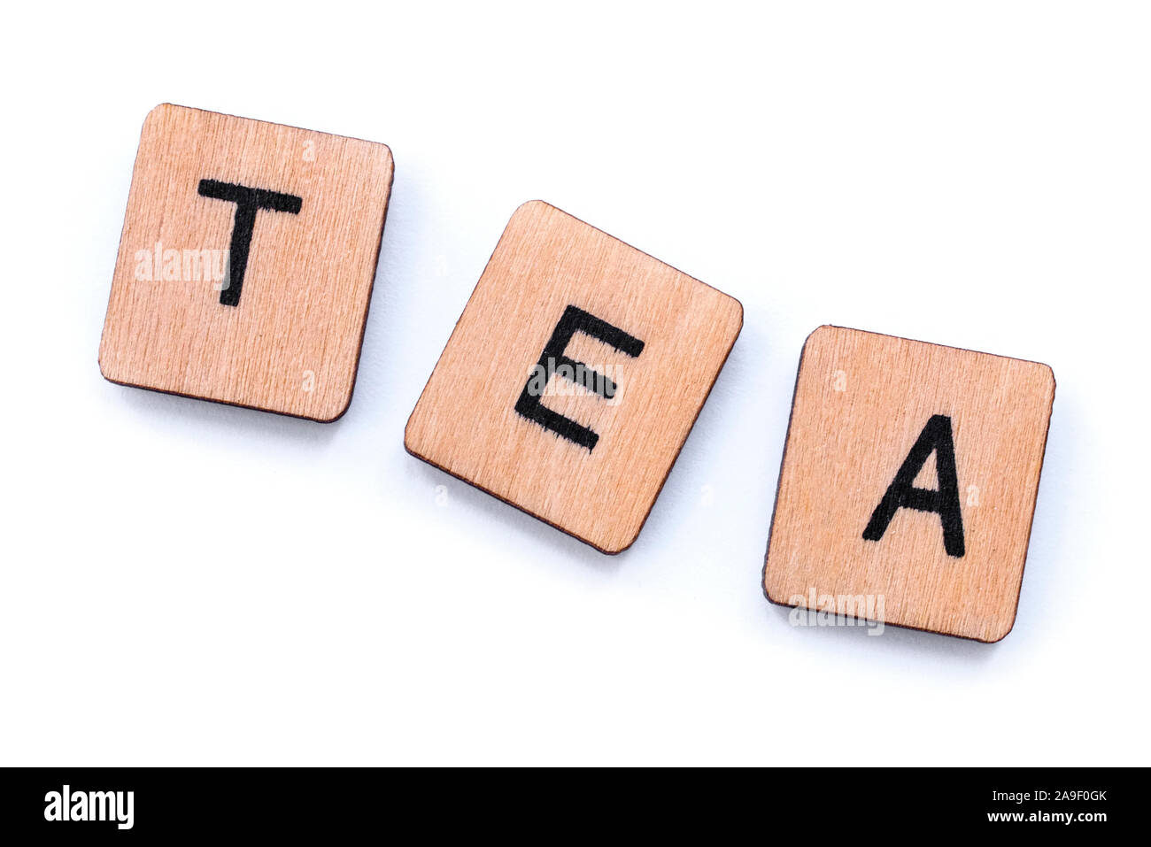 The word TEA, spelt with wooden letter tiles over a white background ...