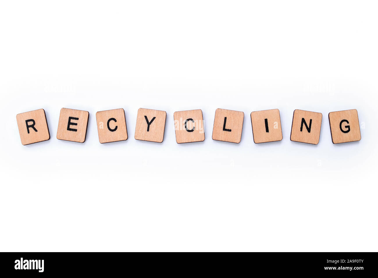 The word RECYCLING, spelt with wooden letter tiles over a white ...