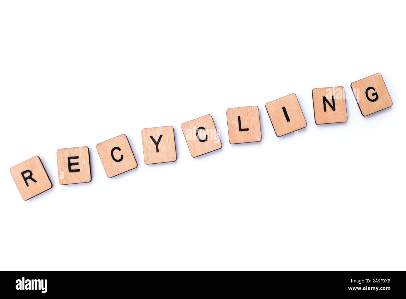 The word RECYCLING, spelt with wooden letter tiles over a white ...