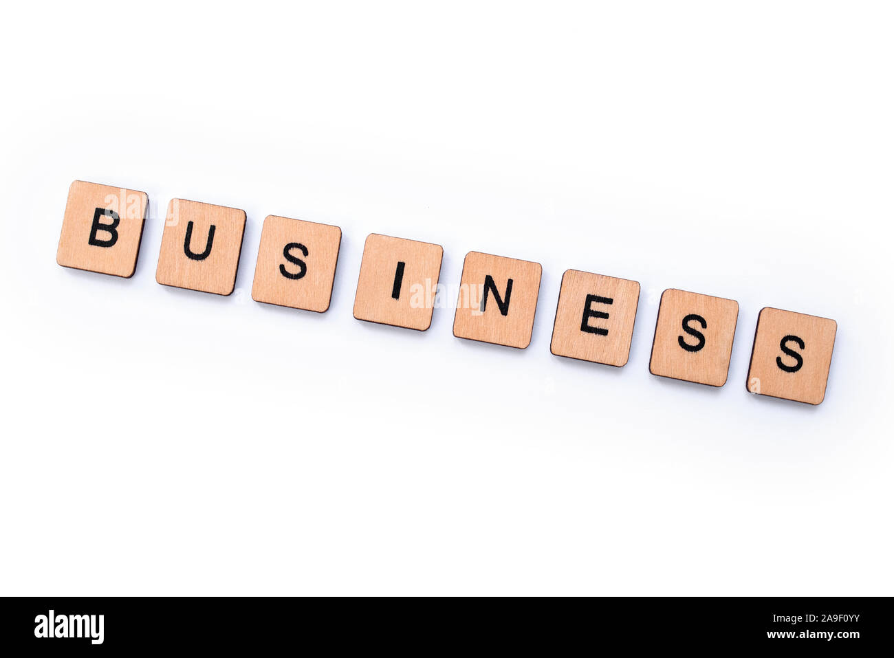The word BUSINESS, spelt with wooden letter tiles over a white ...