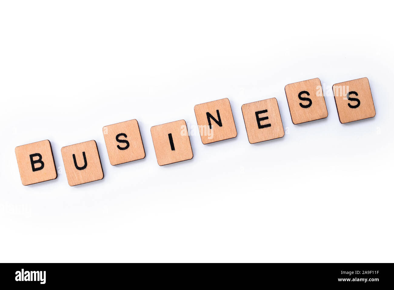 The word BUSINESS, spelt with wooden letter tiles over a white ...