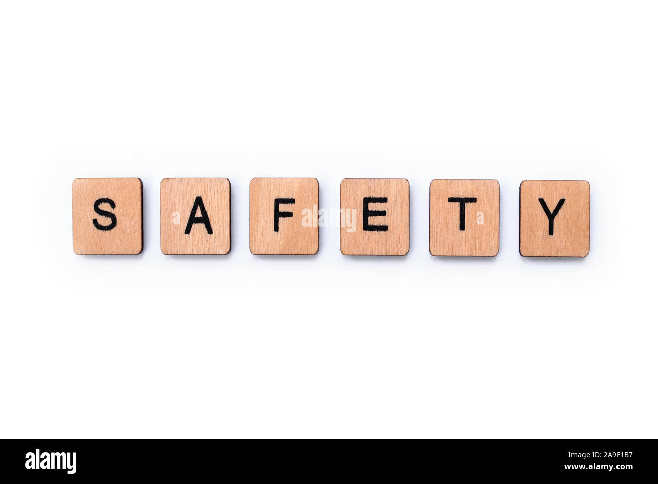 The word SAFETY, spelt with wooden letter tiles over a white background ...