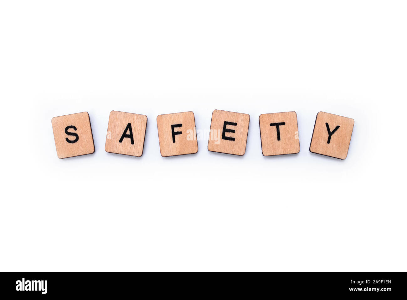 The word SAFETY, spelt with wooden letter tiles over a white background ...