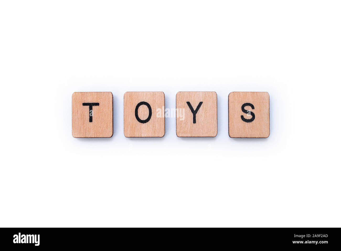 The word TOYS, spelt with wooden letter tiles over a white background ...
