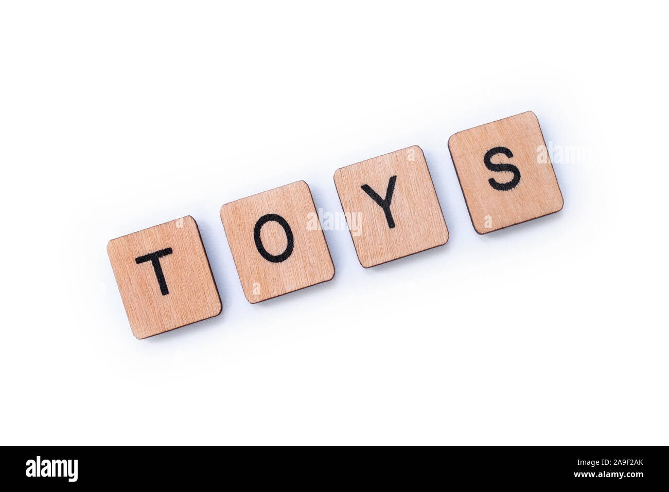 The word TOYS, spelt with wooden letter tiles over a white background ...