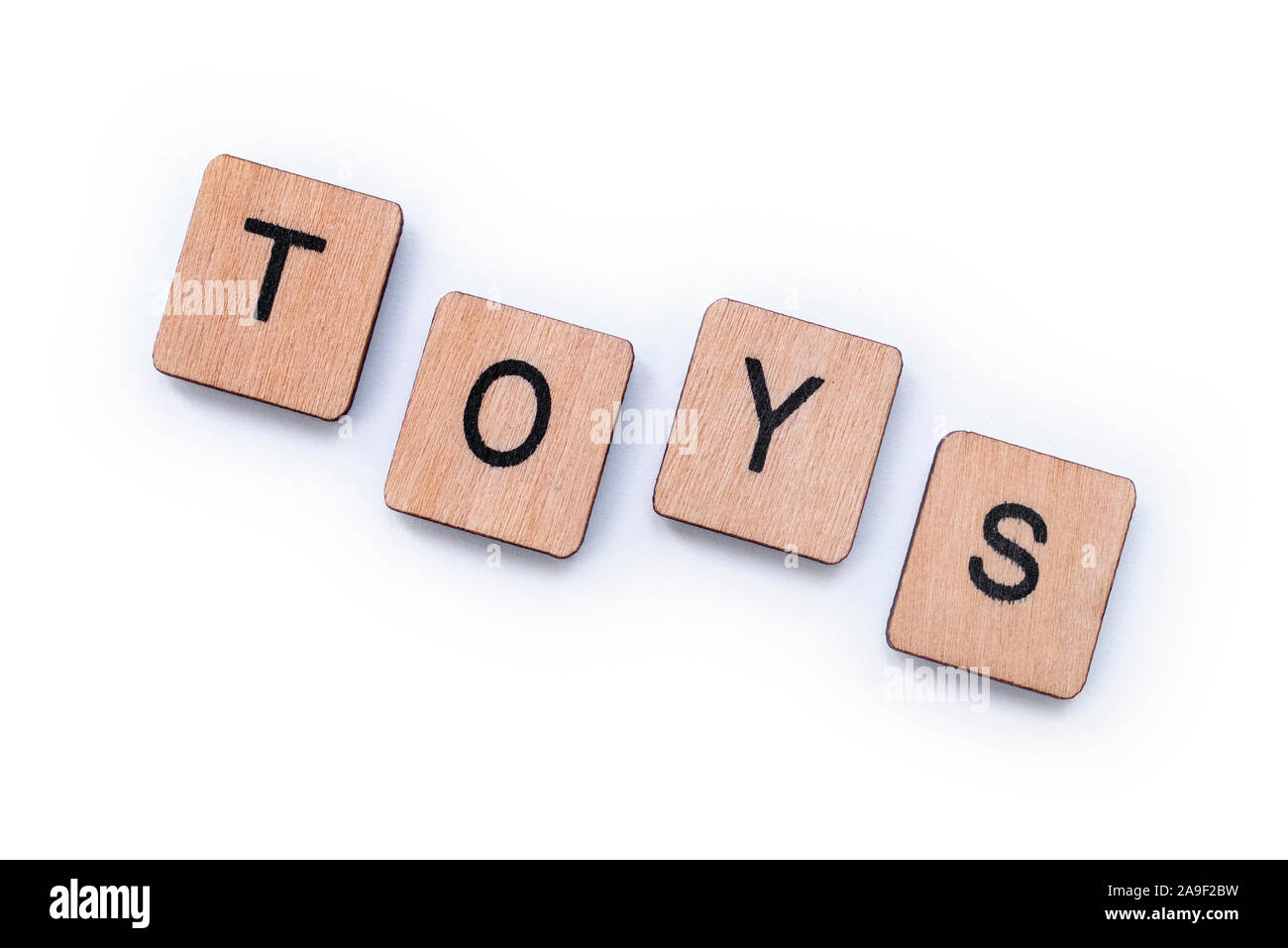 The word TOYS, spelt with wooden letter tiles over a white background ...