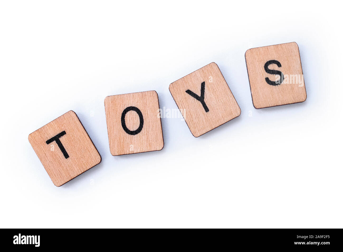 The word TOYS, spelt with wooden letter tiles over a white background ...