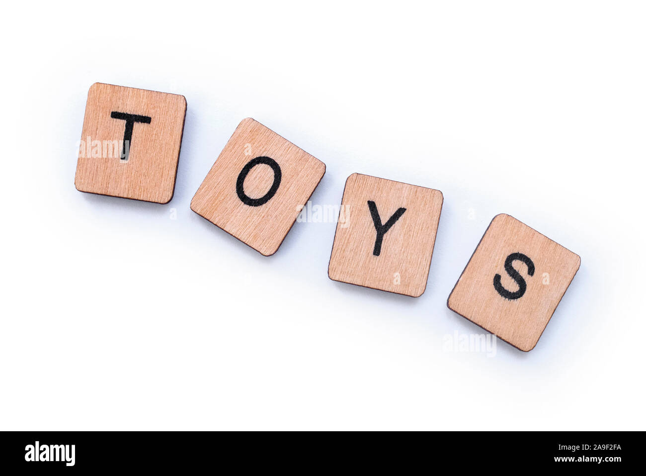 The word TOYS, spelt with wooden letter tiles over a white background ...