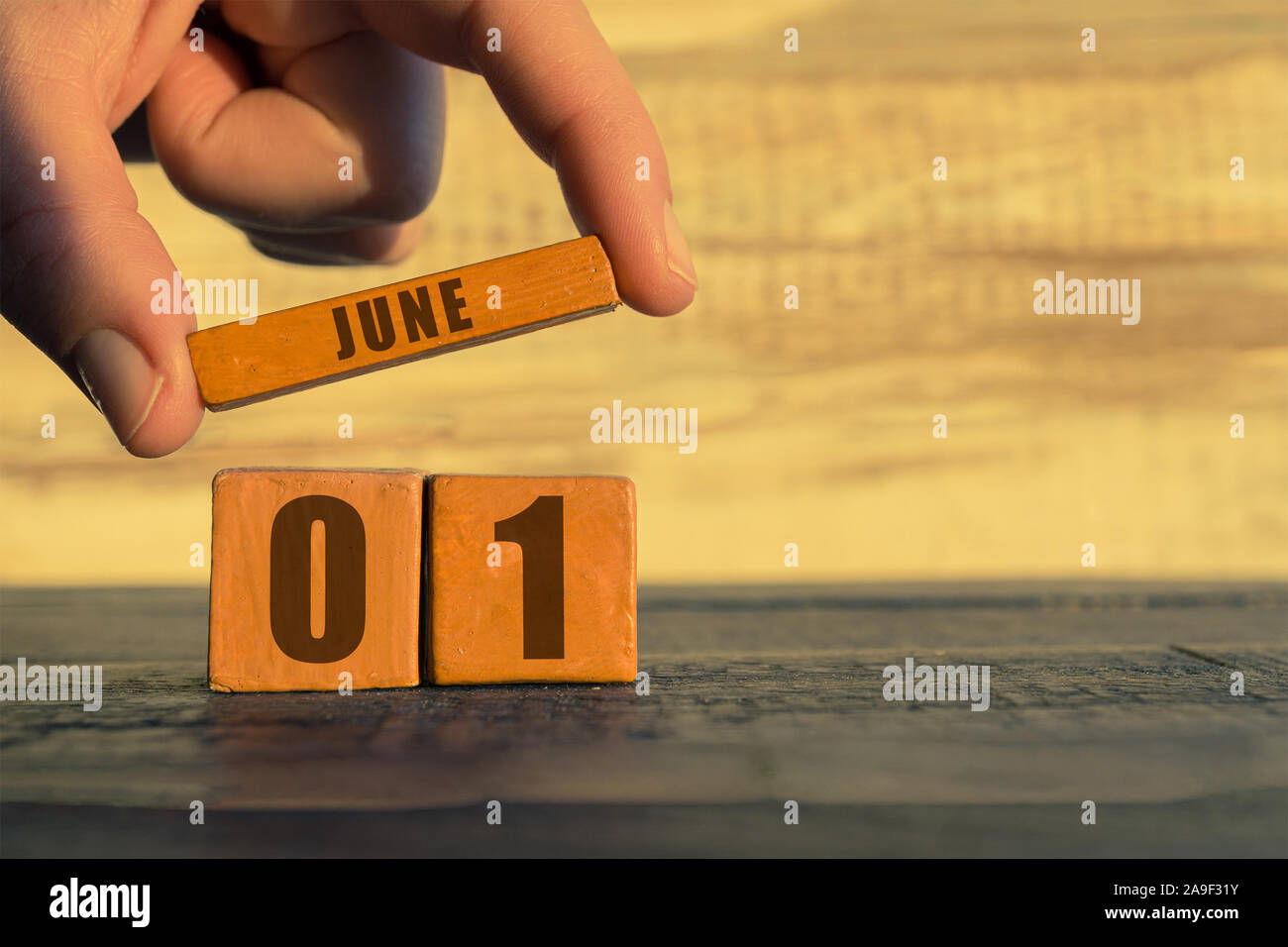 june 1st. Day 1 of month, calendar on a wooden cube. a woman's hand ...