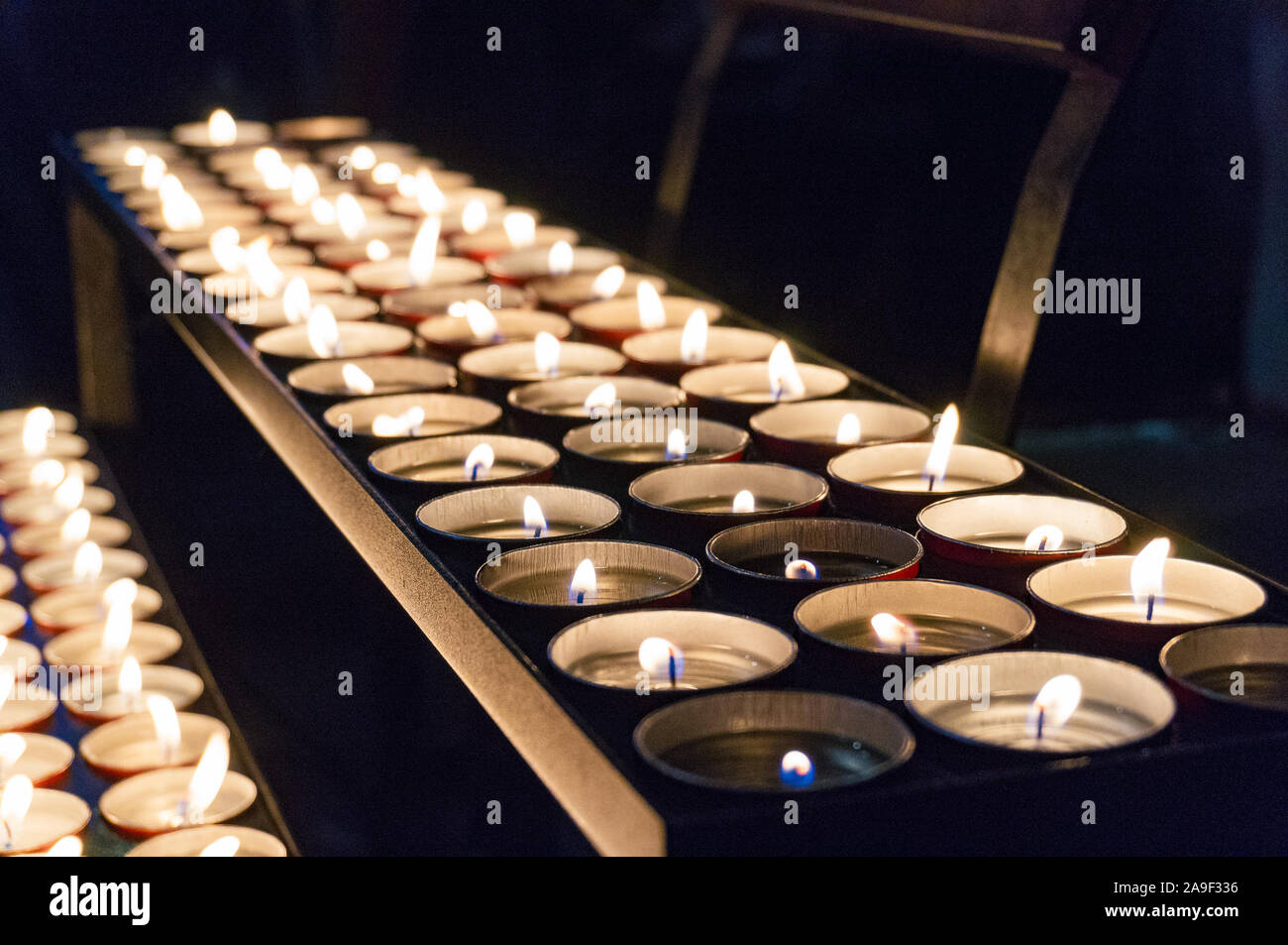 Lighted tea candles in a row on dark background Stock Photo - Alamy