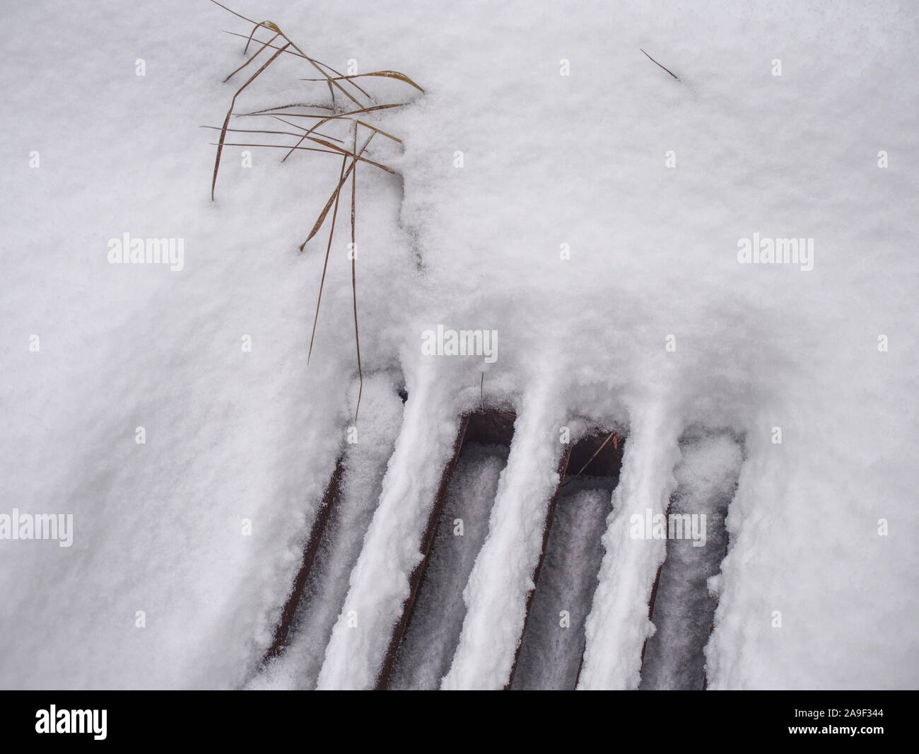 White snow on metal grate outside pavement road. White snowflakes flows ...