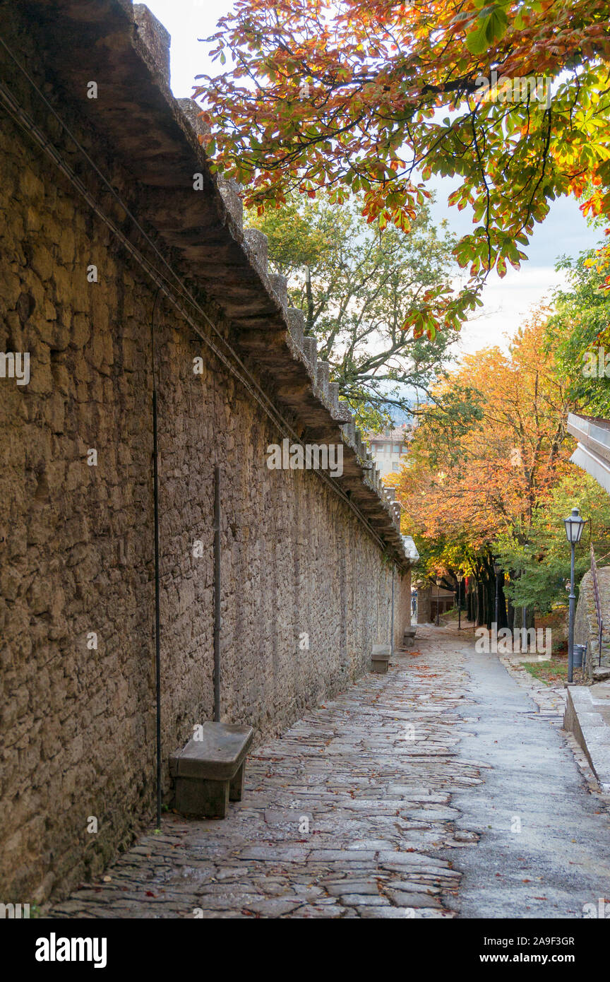 Alley walkway, path in autumn park with colorful trees and stone wall ...