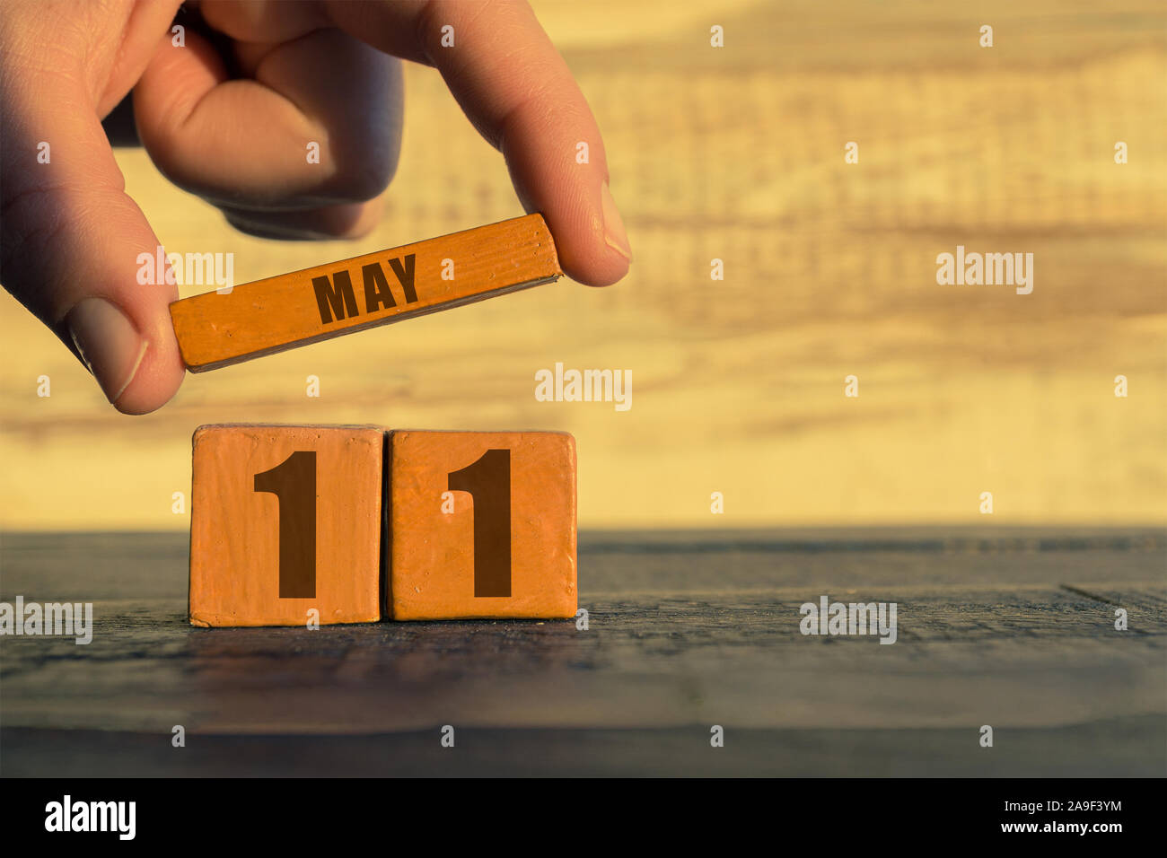 may 11th. Day 11 of month, calendar on a wooden cube. a woman's hand ...
