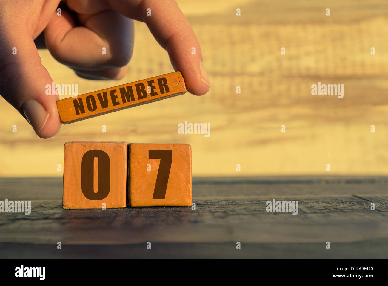 november 7th. Day 7 of month, calendar on a wooden cube. a woman's hand ...