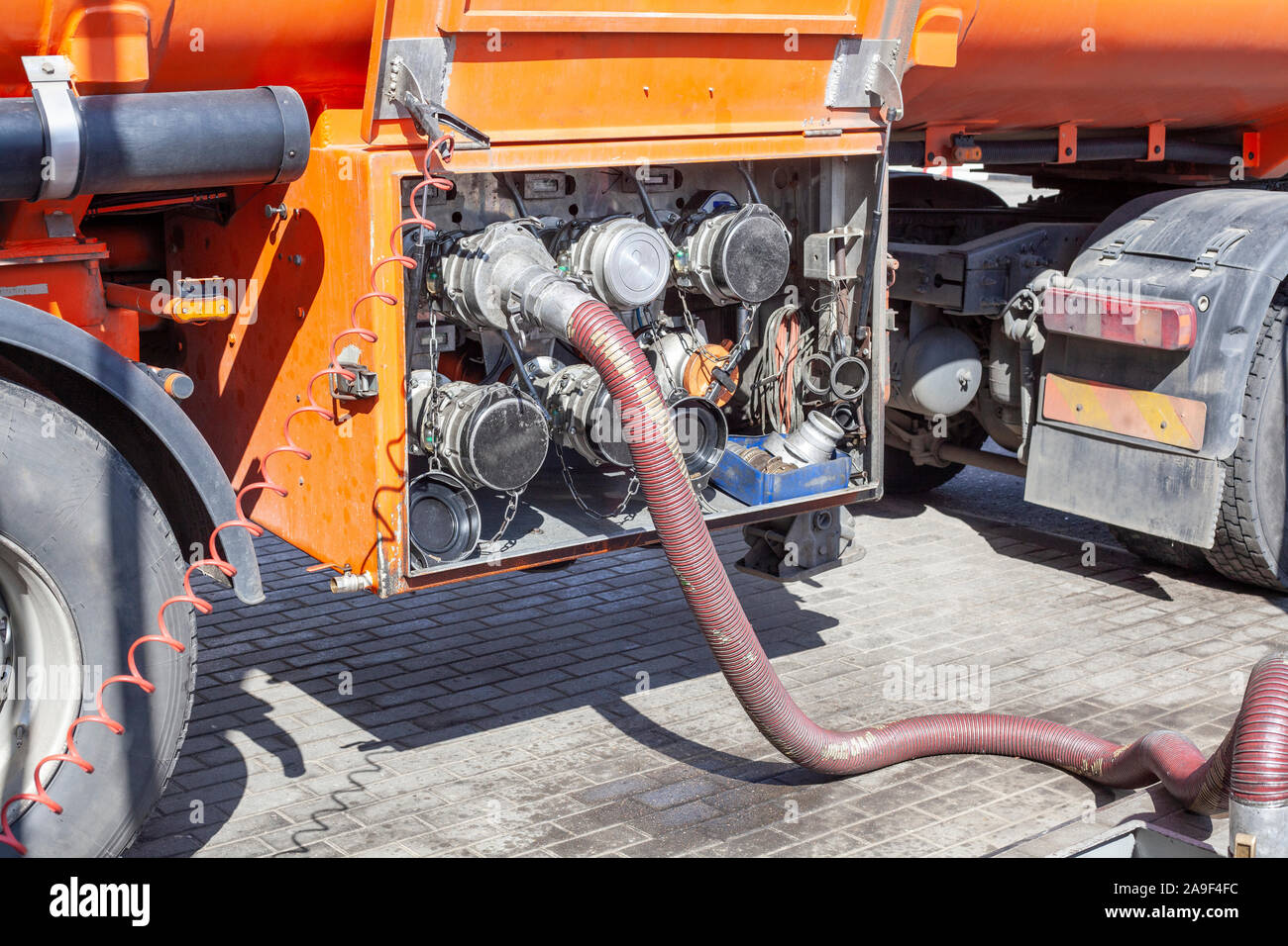 A fuel truck pumps gasoline through a hose to a gas station. A gas ...