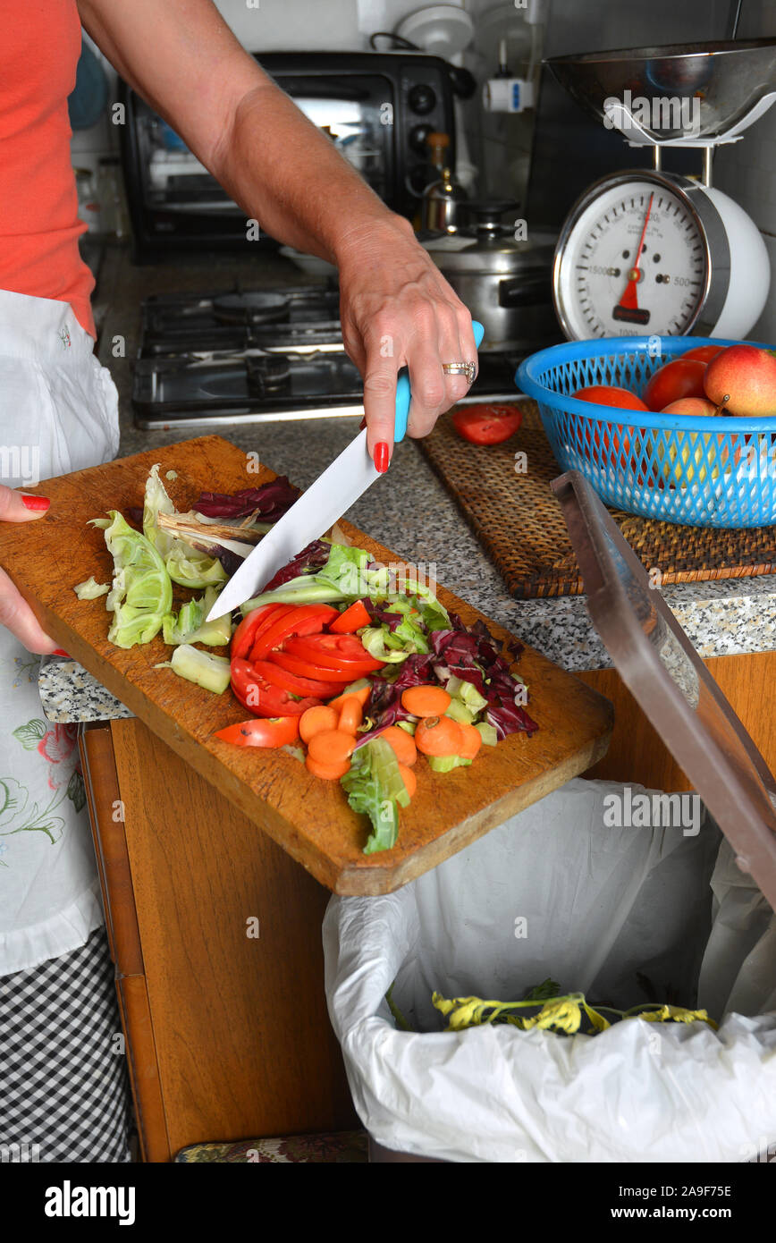 Detail of a female hand disposing of organic waste in a proper bin with ...