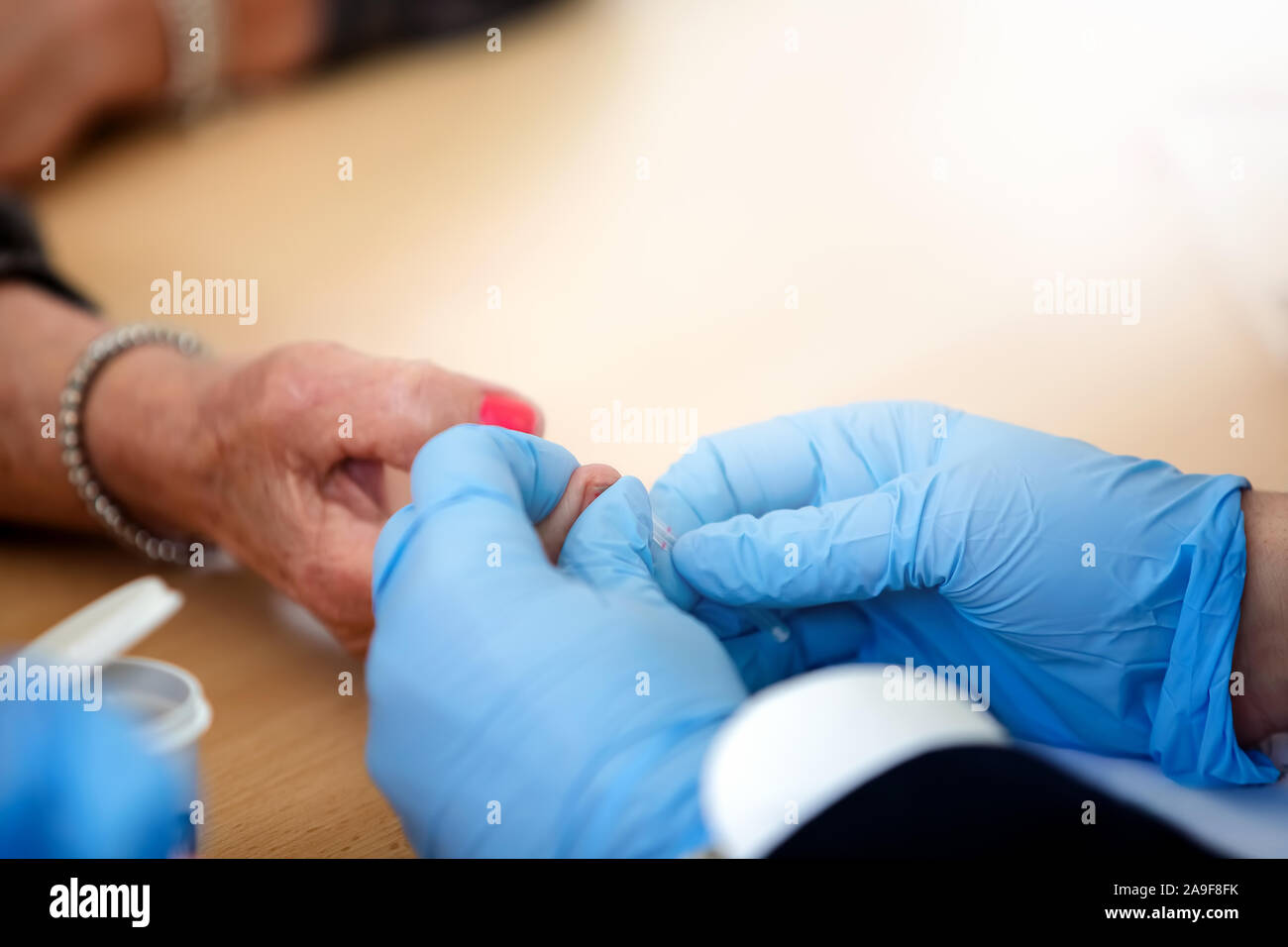 Blood glucose control in the blood of an elderly woman. Taking a blood ...