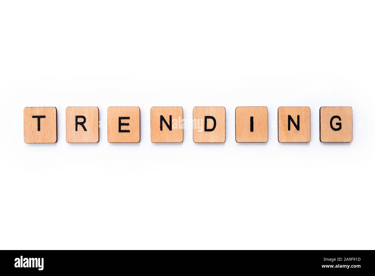 The word TRENDING, spelt with wooden letter tiles over a white ...